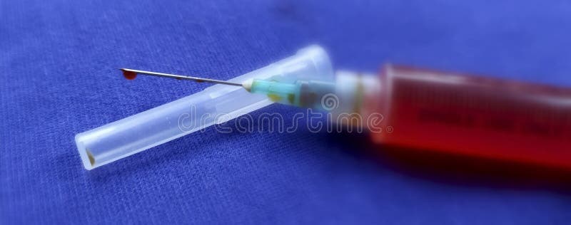 Close-up of a Syringe with Cannula and Drop in Front of Dark Blue ...