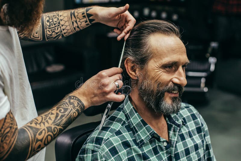 Positive Man Smiling and Barber with Tattoos Doing Haircut for Him ... Positive Man Smiling and Barber with Tattoos Doing Haircut for Him ...