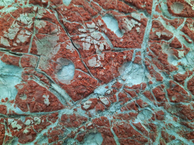 A Close-up of a Textured Rock Surface with Deep Red and Pale Blue-green ...