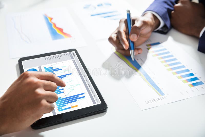 Two Businesspeople Using Digital Tablet while Working on Graph Stock ...