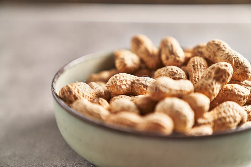 Close-up of Unshelled Peanuts in a Bowl on a Textured Tabletop, Hinting ...