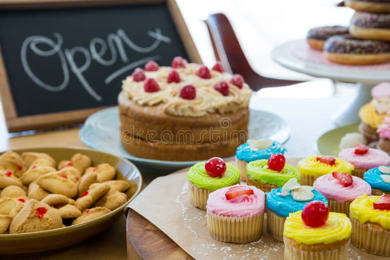 Close-up of Various Sweet Foods on Table with Open Signboard Stock ...