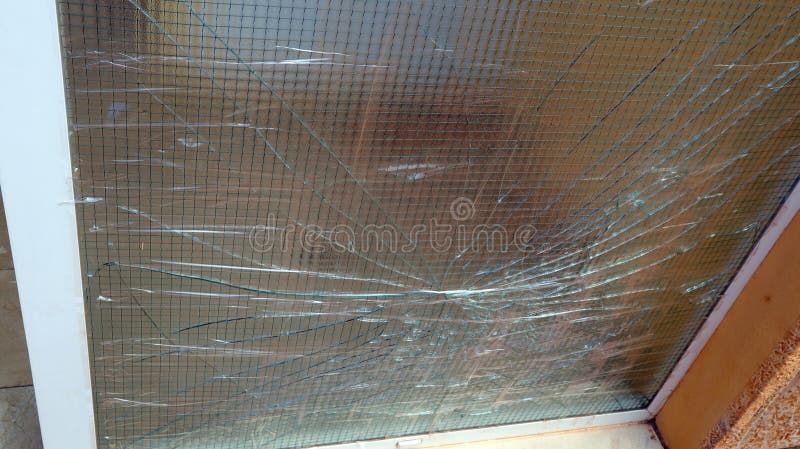 Close-up View of Broken Windowpane with a Wire Mesh Behind it. Glass is ...