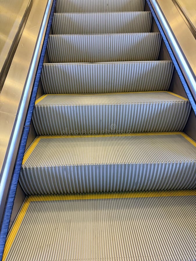 Close-up View of an Escalator with Metallic Grooved Steps and Yellow ...