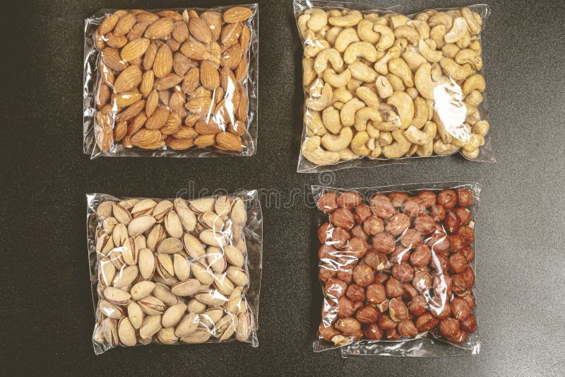 Four Packages Filled with Different Nuts and Peanuts on Top of a Table ...