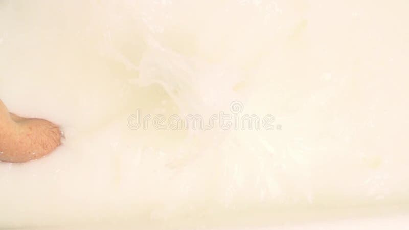 Close-up View of a Hand Coming Out from a Milk Bath and Sinking Back ...
