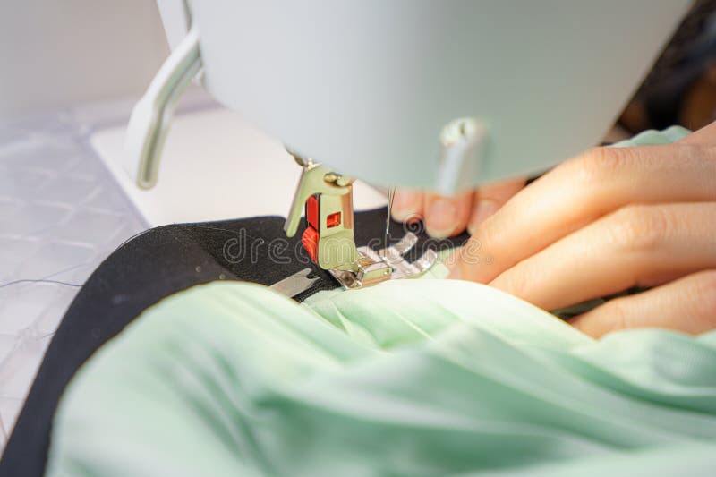 Close-up View of Hands Sewing Fabric with a Sewing Machine in a Bright ...