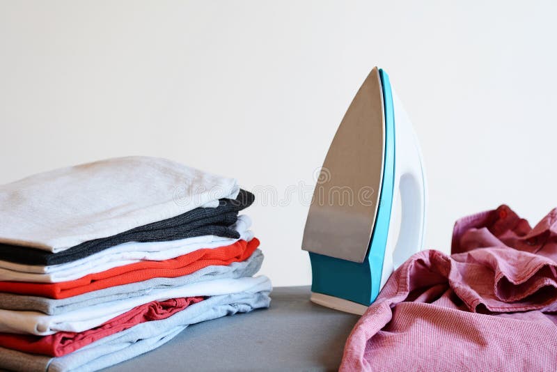Close Up View of Iron Clothes on Ironing Board with Stack of Ironed ...
