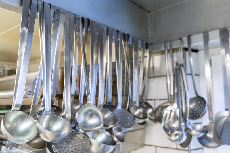 Close Up View of Many Soup Ladles Hanging from a Wall Rack in a ...