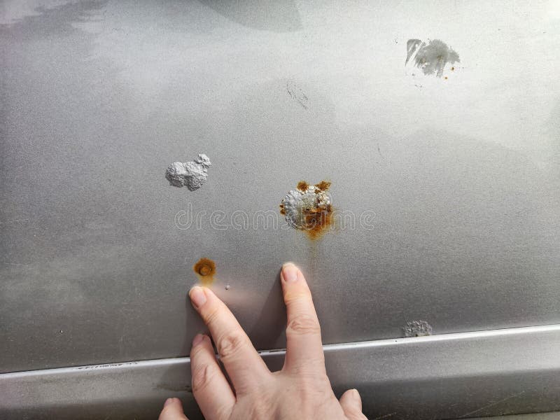 Close-up View of Rust Damage on a Silver Vehicle Surface with a Hand ...