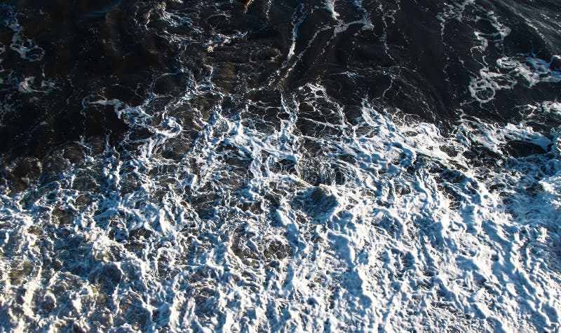Close-up View of White Foam Breaking Against Dark Ocean Rocks Stock ...