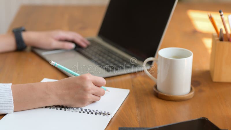 Close-up View of Student Taking Notes on Her Exam while Using Laptop ...