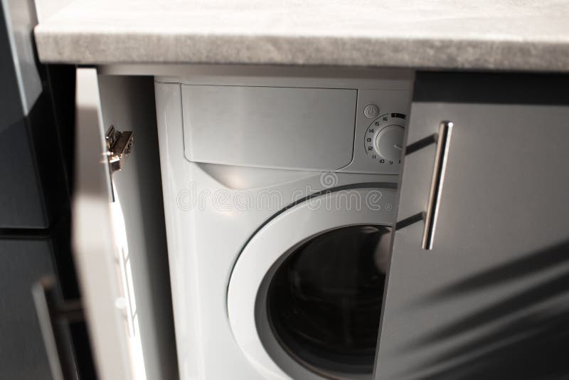 Close-up of Washing Machine Inside Kitchen Cabinet with Opened Doors ...