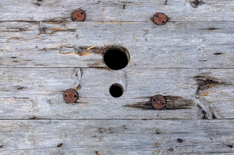 A Close-up of a Weathered Wooden Surface with Two Holes and Five Screws ...