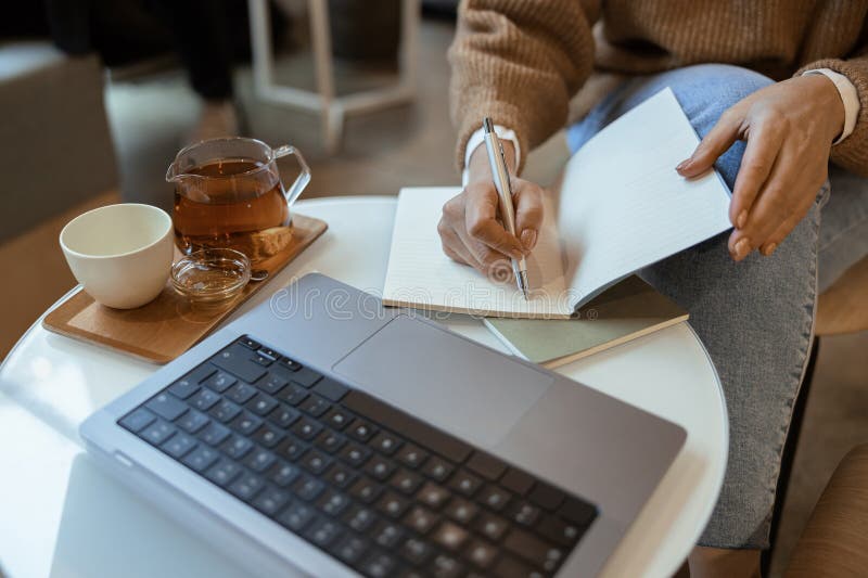 Close Up of Woman Making Notes in Notepad while Working Laptop in Cafe ...