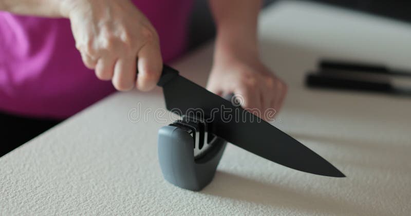 Close-up of Woman Sharpening Knife with Knife Sharpener on the Kitchen ...