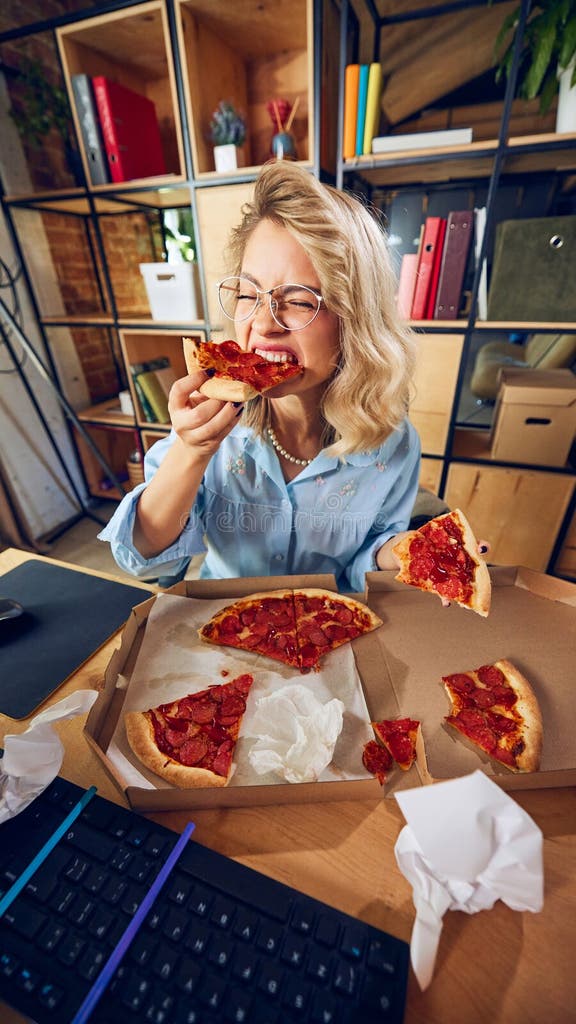 Close-up of Worker Biting into Pizza Slice, Clearly Distracted from ...