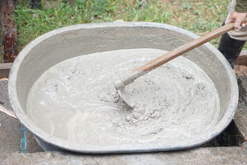 Close Up Worker Using a Hoe To Mix Cement in Basin for Mixing Cement ...