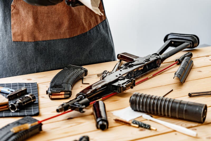 Close Up of Young Man in Apron Disassembling a Gun Above the Table ...