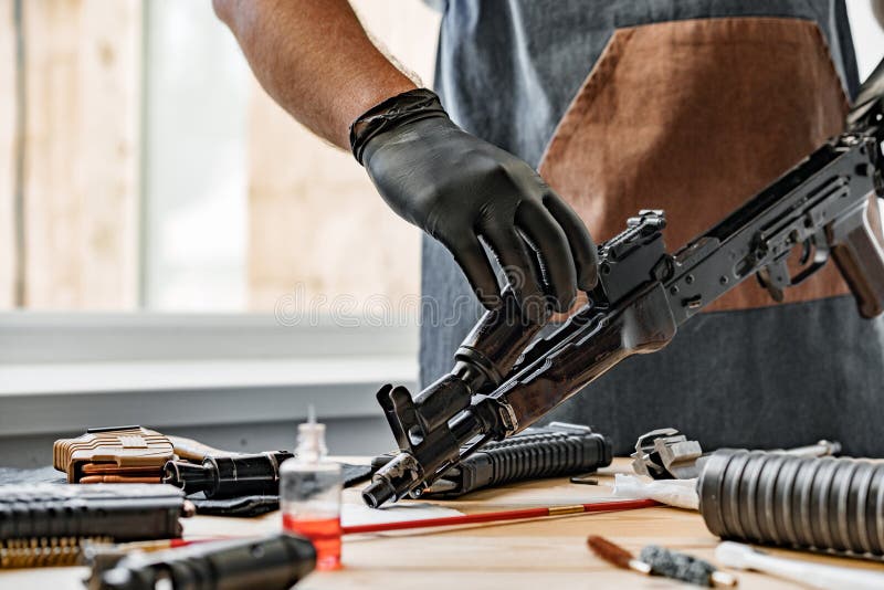 Close Up of Young Man in Apron Disassembling a Gun Above the Table ...