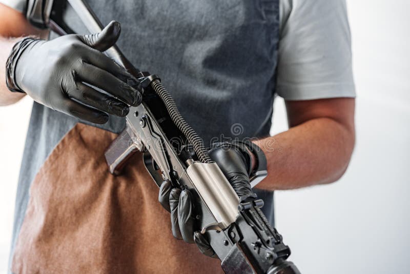 Close Up of Young Man in Apron Disassembling a Gun Above the Table ...