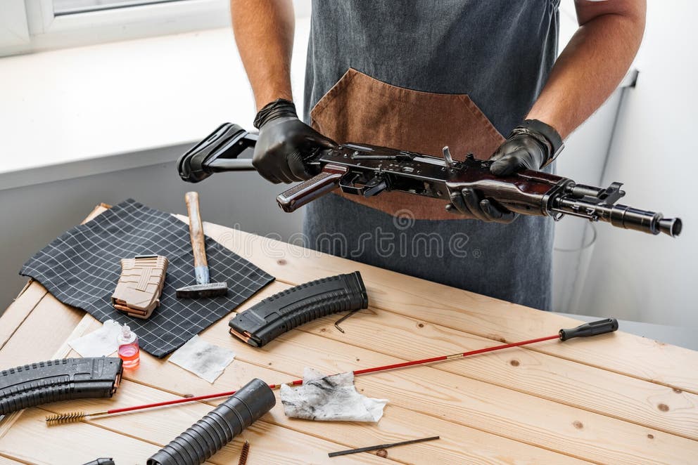 Close Up of Young Man in Apron Disassembling a Gun Above the Table ...