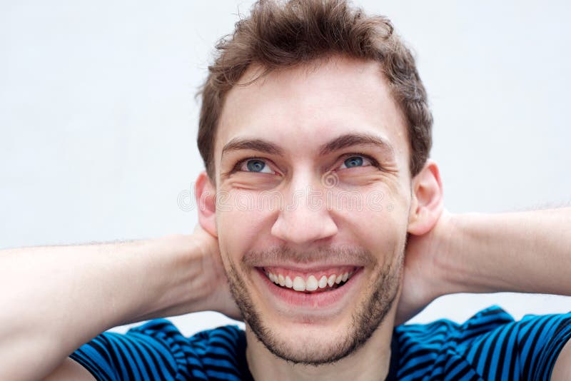 Happy Young Man Smiling with Hands Behind Head by Gray Wall Stock Photo ...