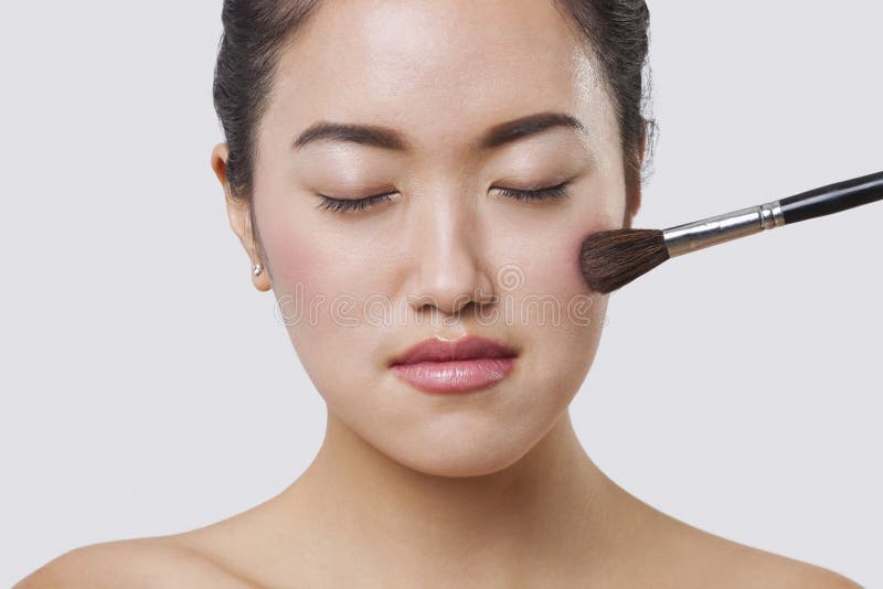 Close-up of Young Woman Applying Blush Over White Background Stock ...