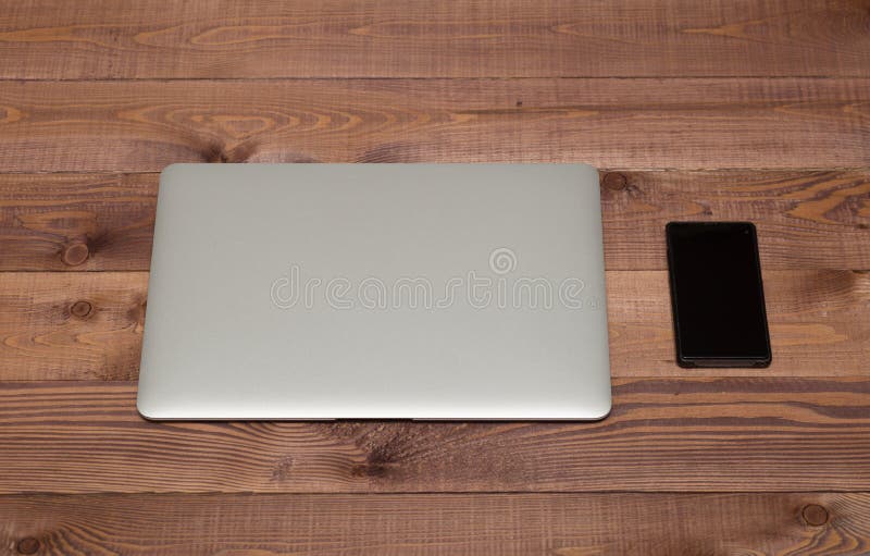 Closed Silver Laptop and Smartphone on Brown Wooden Table Stock Photo ...