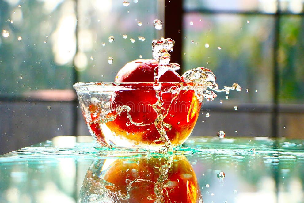 Closeup of an Apple Falling into a Bowl of Water Splashing on the Table ...