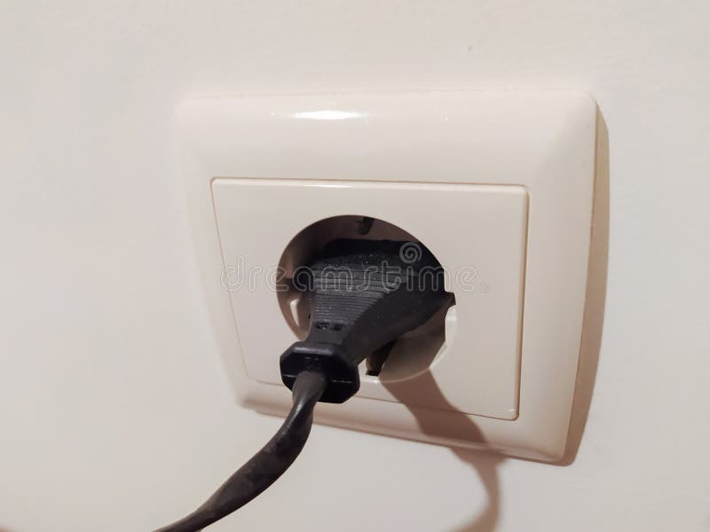 Closeup of a Black Electrical Plug Inserted into a Creamcolored Wall ...