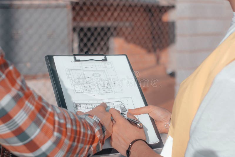 Closeup of Builders Pointing at the Construction Design while Standing ...