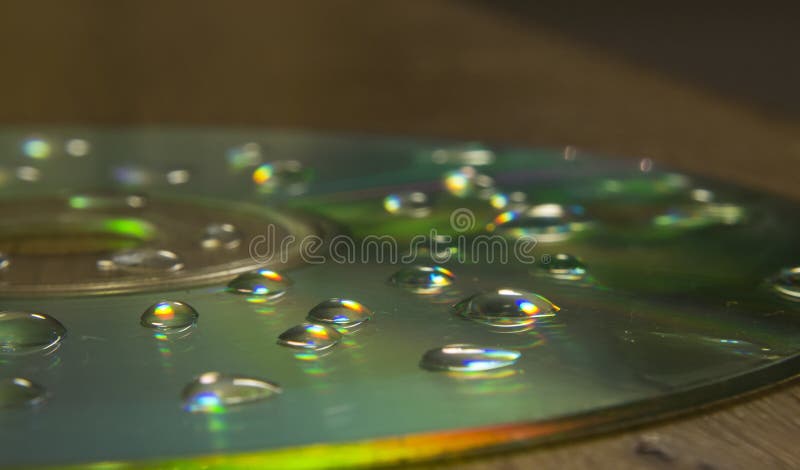Closeup of a CD with Water Drops on it on the Table Under the Lights ...