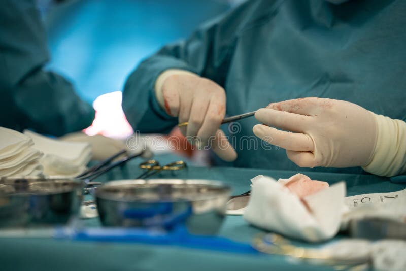 Closeup of a Doctor with Surgical Tools Under the Lights with a Blurry ...