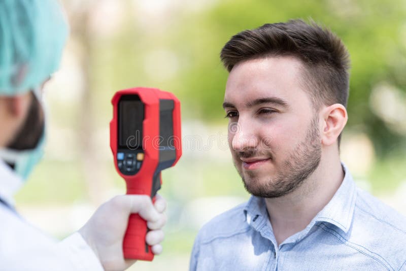 Closeup of a Doctor Using a Infrared Thermometer on a Patient in a Park ...