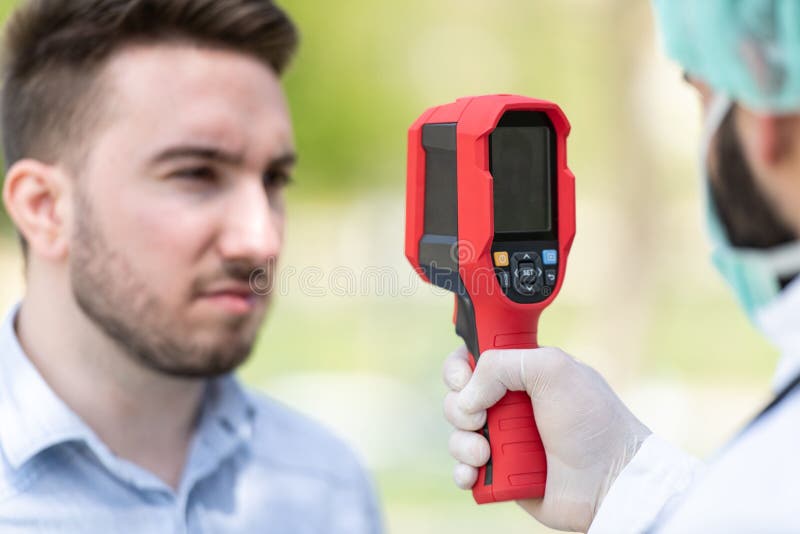 Closeup of a Doctor Using a Infrared Thermometer on a Patient in a Park ...