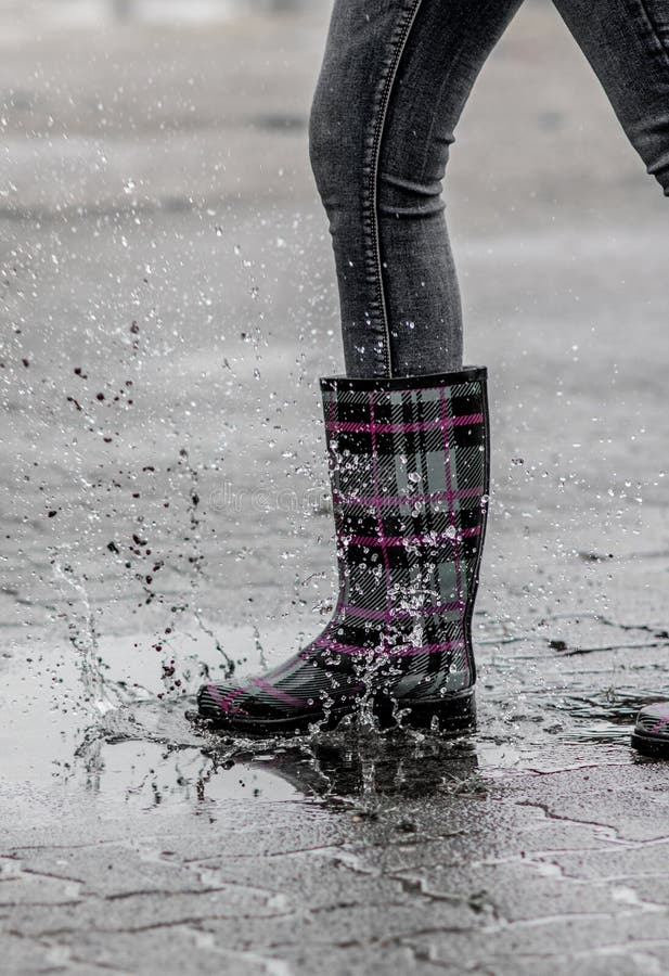 Closeup of a Female Foot in a Stylish Rubber Boot Jumping into a Puddle ...