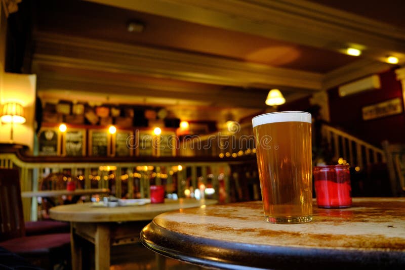 Closeup of a Glass of Beer on the Table Under the Lights in the Bar ...