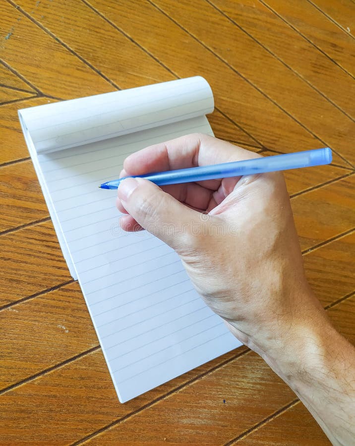 Closeup of a Hand Writing on a Lined Notepad with a Blue Pen, Resting ...