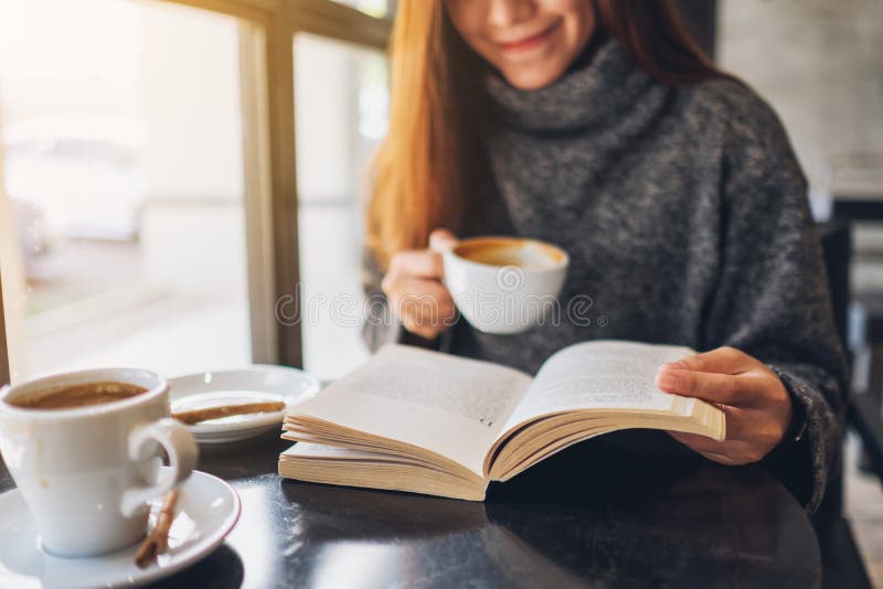 A Beautiful Woman Reading a Book while Drinking Coffee in Cafe Stock ...