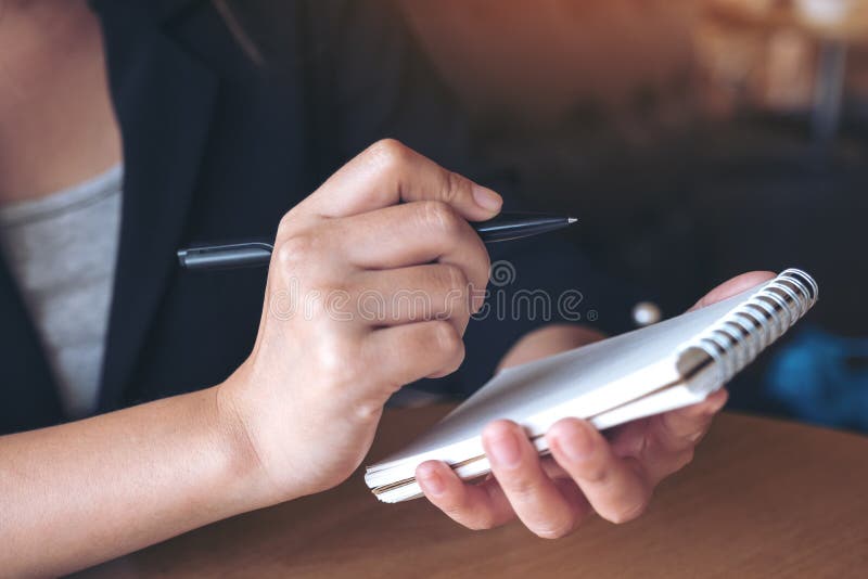 A Hand Holding and Writing Down on a Notebook on Table Stock Photo ...