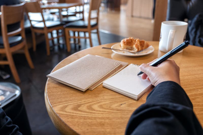 A Hand Writing on Blank Notebook with Coffee Cup and Croissant on Table ...