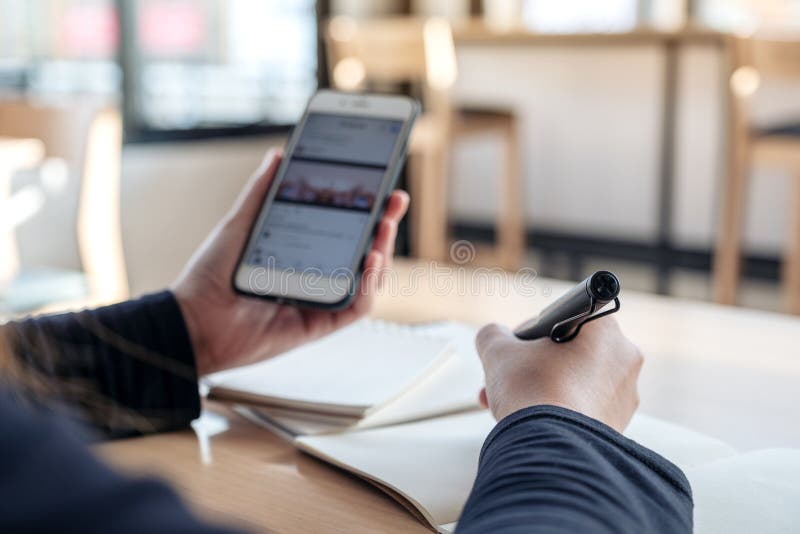 Hands Holding a Smart Phone and a Pen To Write while Working Stock ...