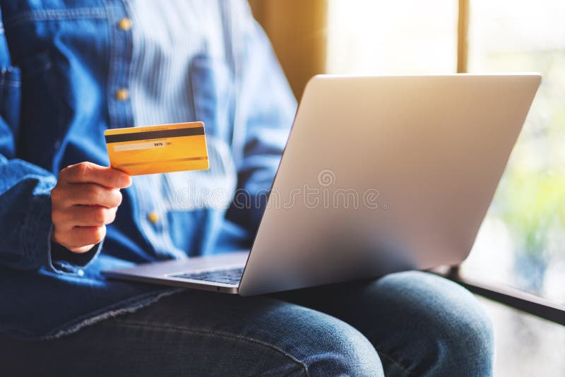 A Woman Holding Credit Cards while Using Laptop Computer Stock Photo ...