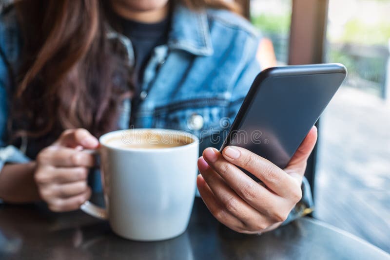 A Woman Holding and Using Mobile Phone while Drinking Coffee Stock ...