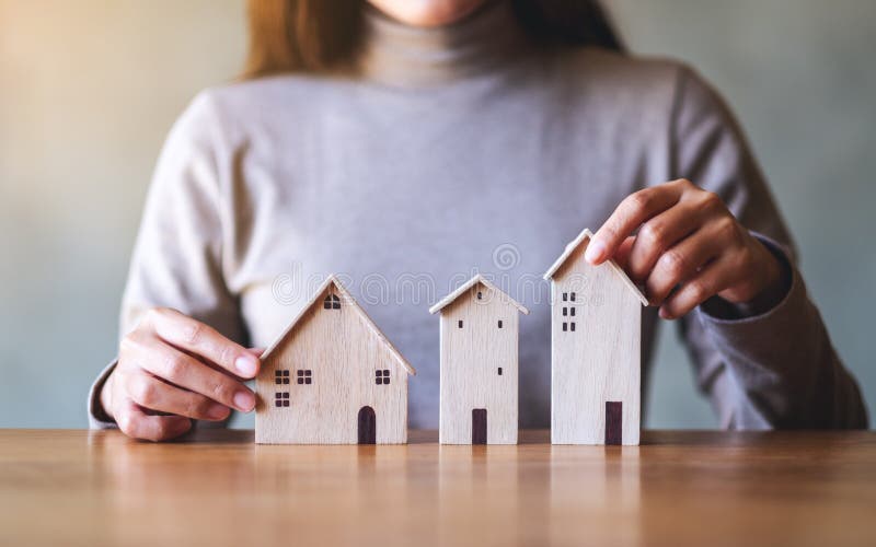 A Woman Holding Wooden House Models on the Table Stock Image - Image of ...