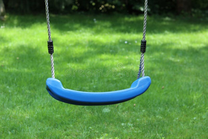 Closeup Landscape Shot of a Blue Swing with Blurry Green Grass in the ...