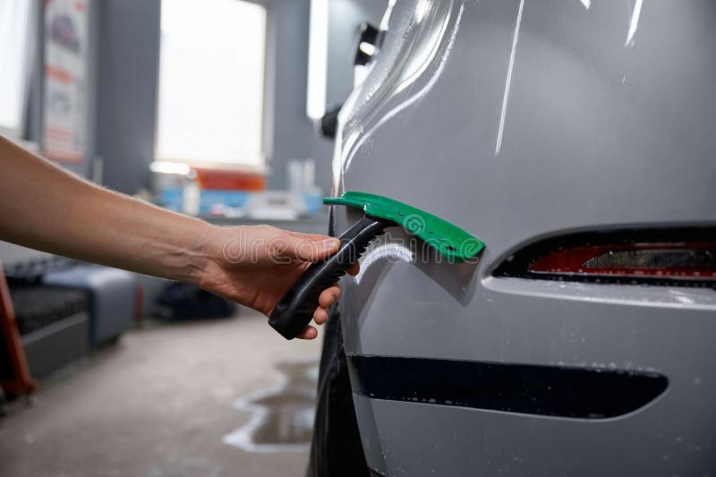 Closeup Master Hand with Rubber Scraper Applying Sticking Protective ...