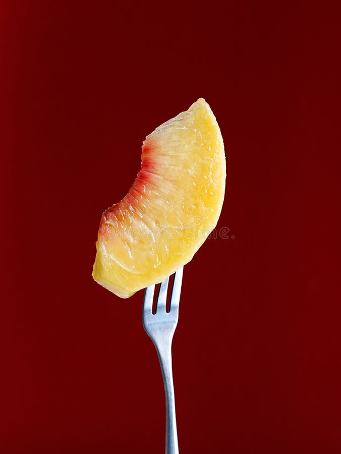 Closeup of a Peach Slice on a Fork in a Maroon Background Stock Image ...