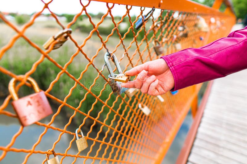 Closeup Shot of a Female Locking a Love Lock on a Bridge during ...